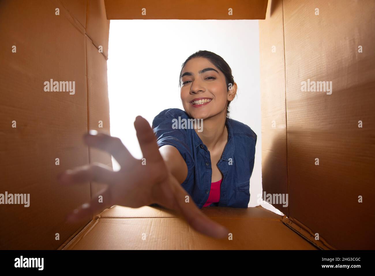 Adult girl raising her hand through cardboard boxes Stock Photo - Alamy