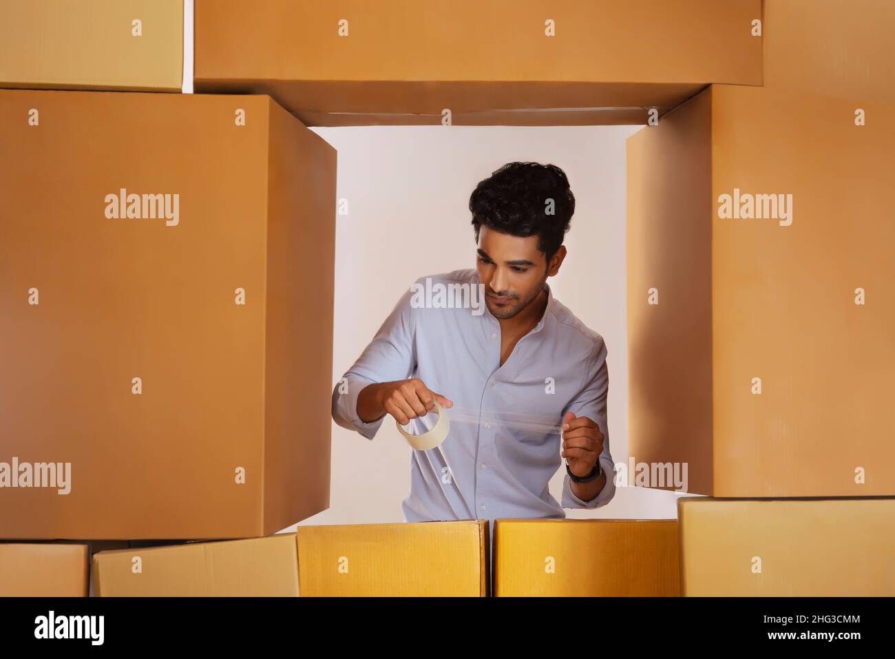Adult boy packing cardboard box with cello tape Stock Photo - Alamy