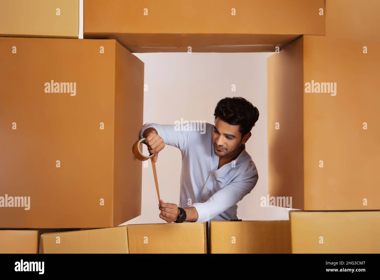Adult boy packing cardboard box with brown tape Stock Photo - Alamy
