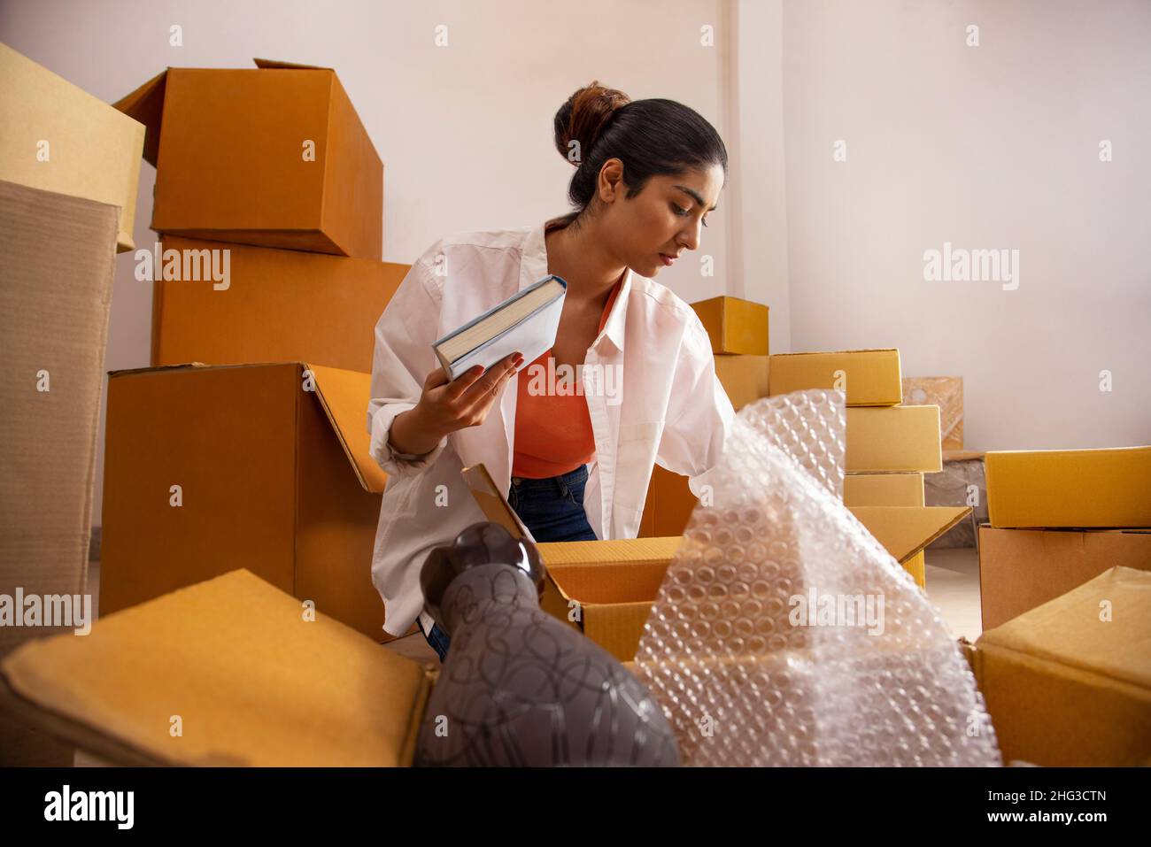 Adult girl packing books into cardboard box Stock Photo - Alamy