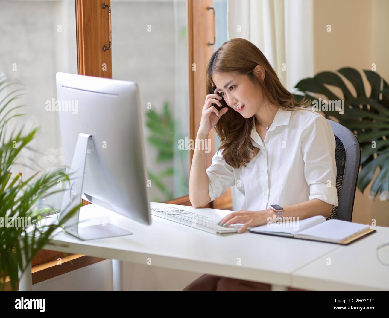 Beautiful young businesswoman working on pc desktop computer, thinking ...