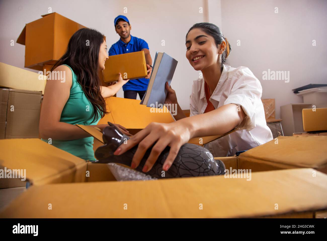 Girls packing flower vase and handing over box to the boy for stacking ...