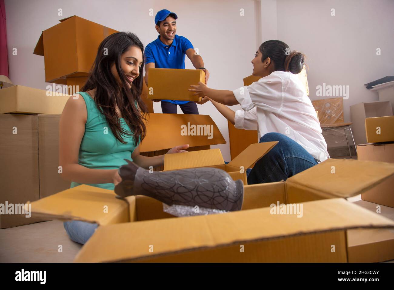 Girls packing household goods and handing over box to the boy for ...