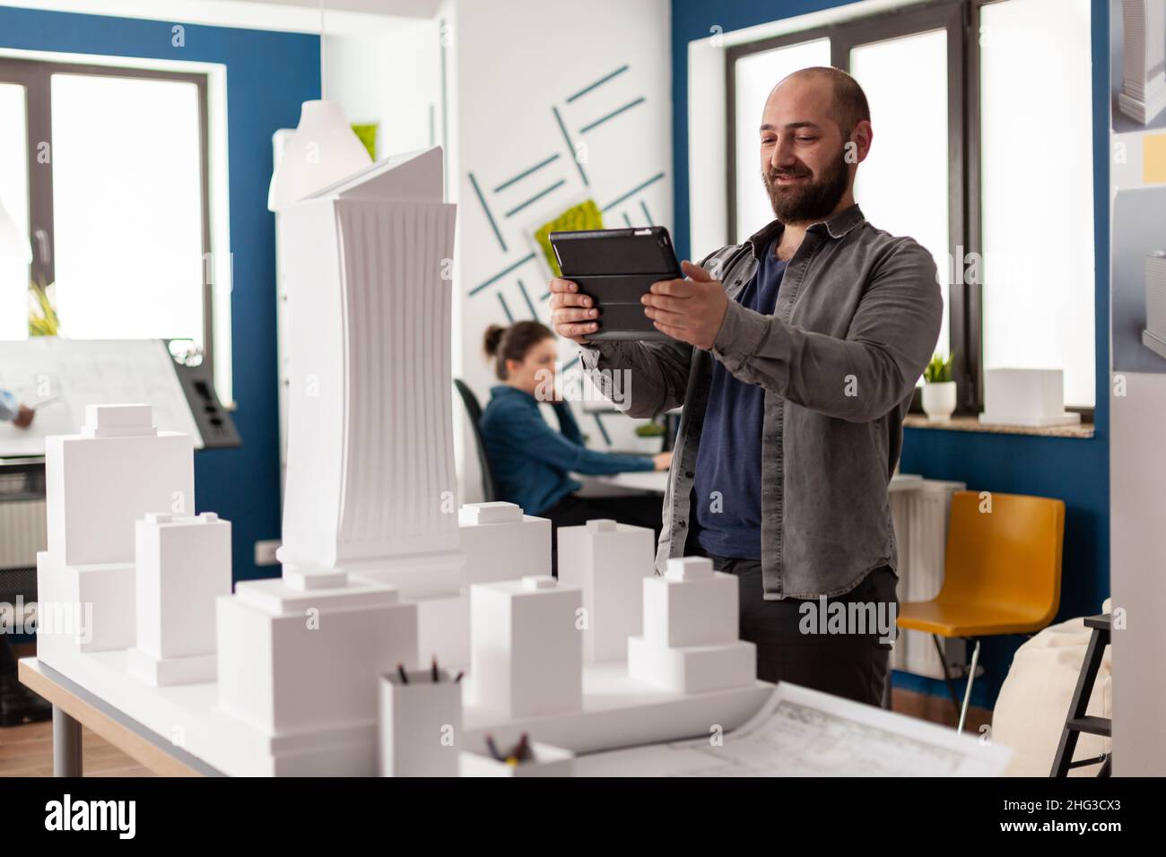 Bearded professional architect looking at tablet in front of white foam ...
