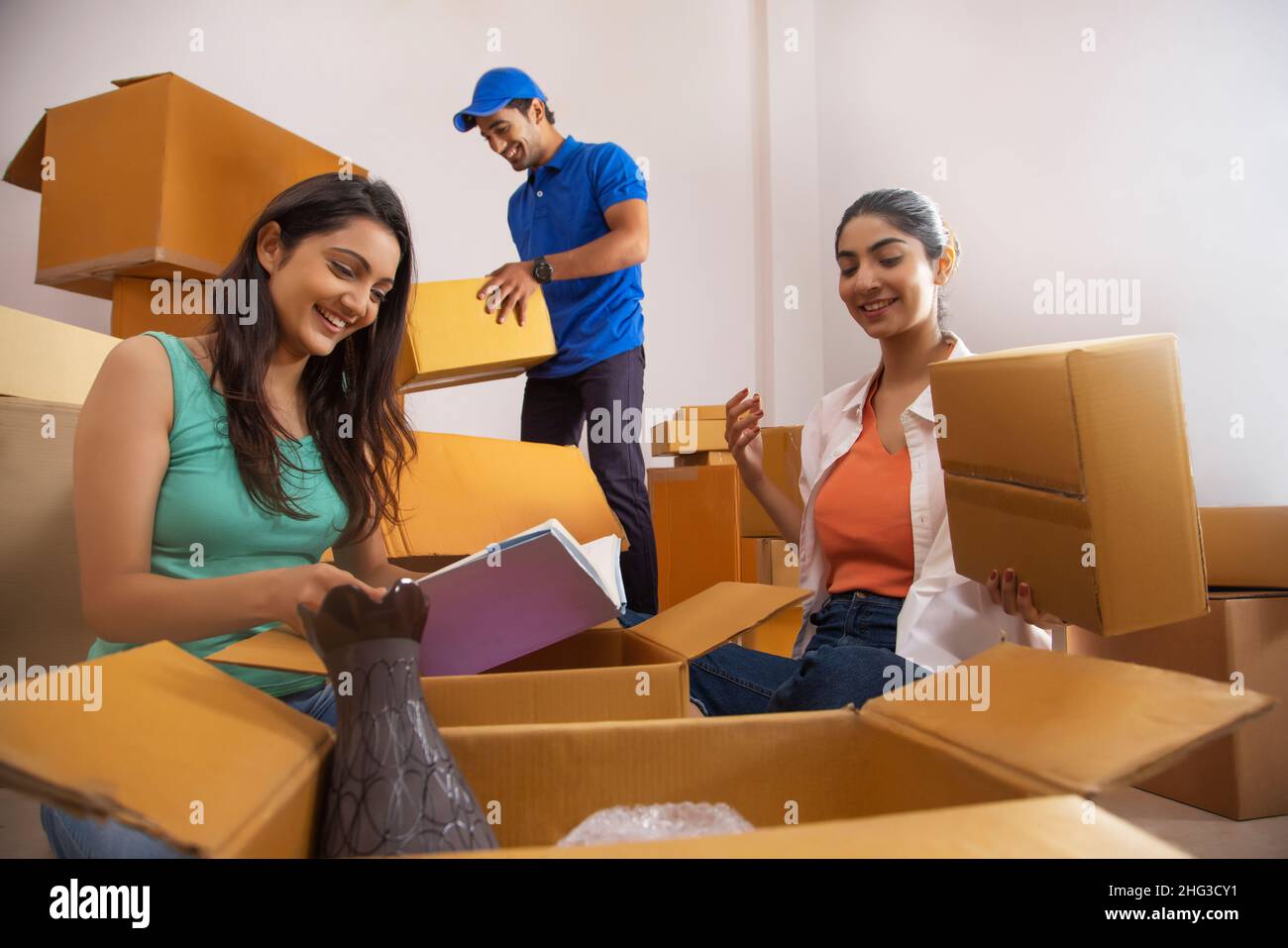 Girls packing household goods and handing over box to the boy for ...