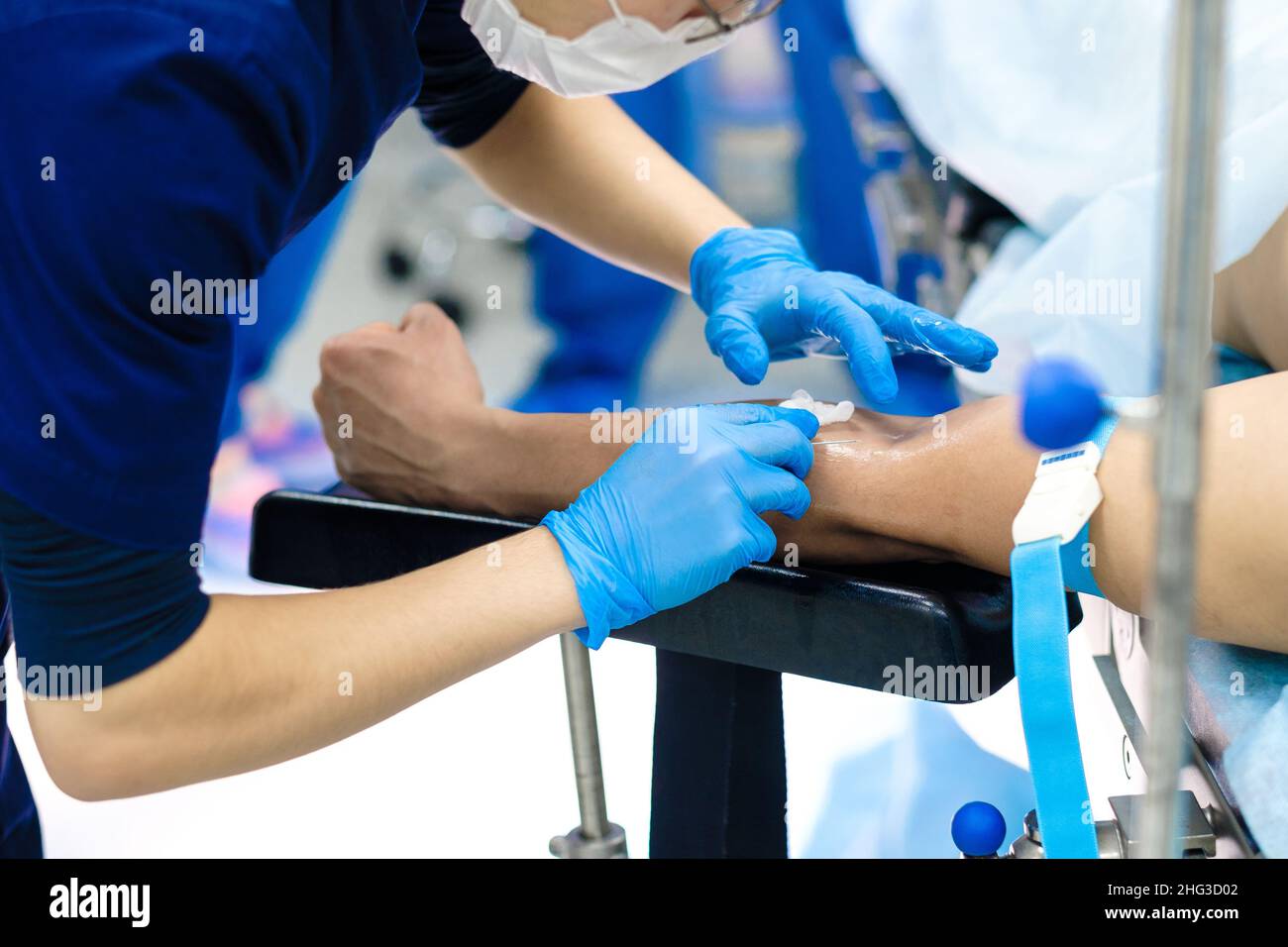 The doctor injects a catheter needle into a vein in the patient's arm ...