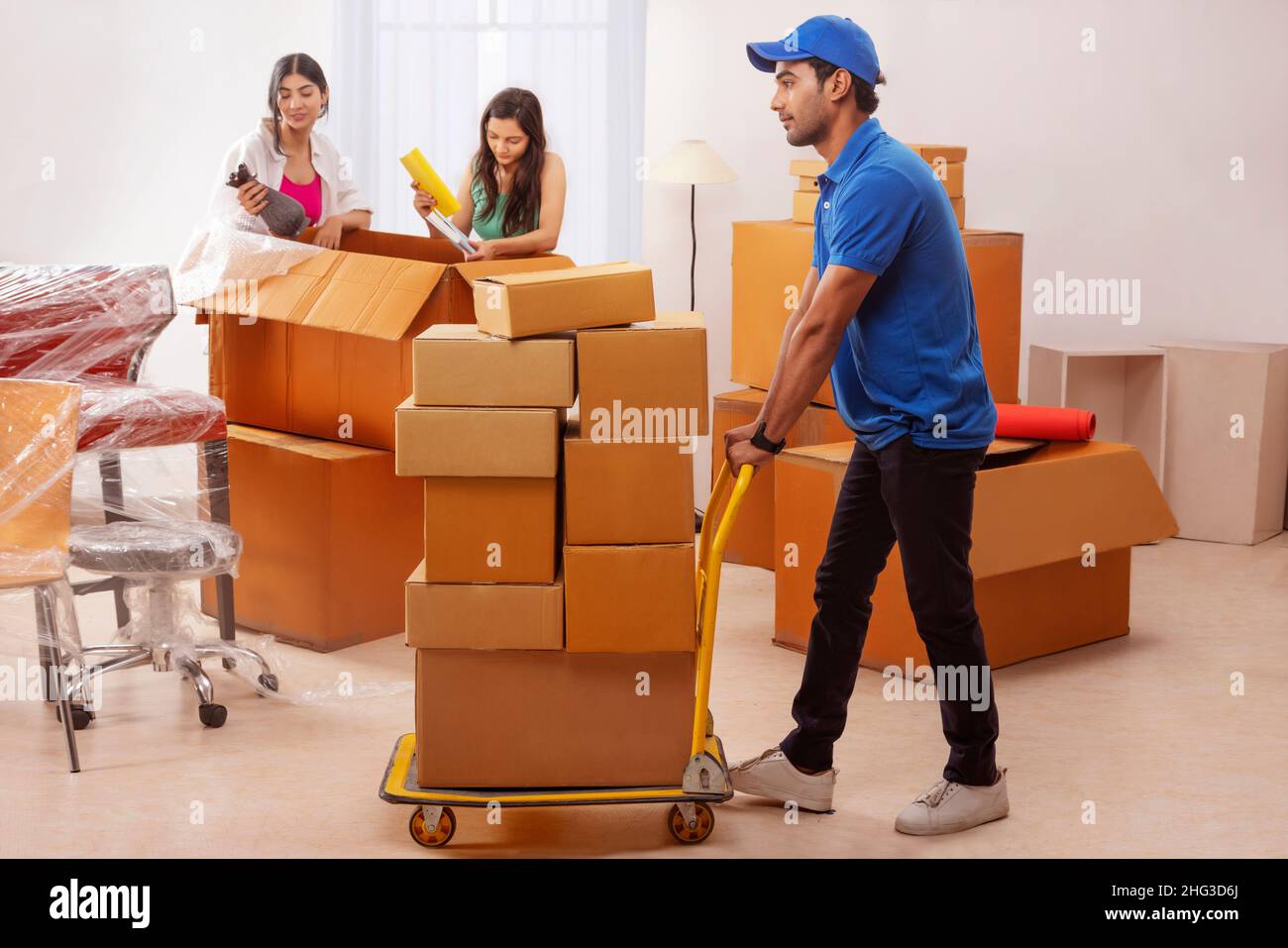 Girls busy with packing while the delivery boy moving boxes to new ...