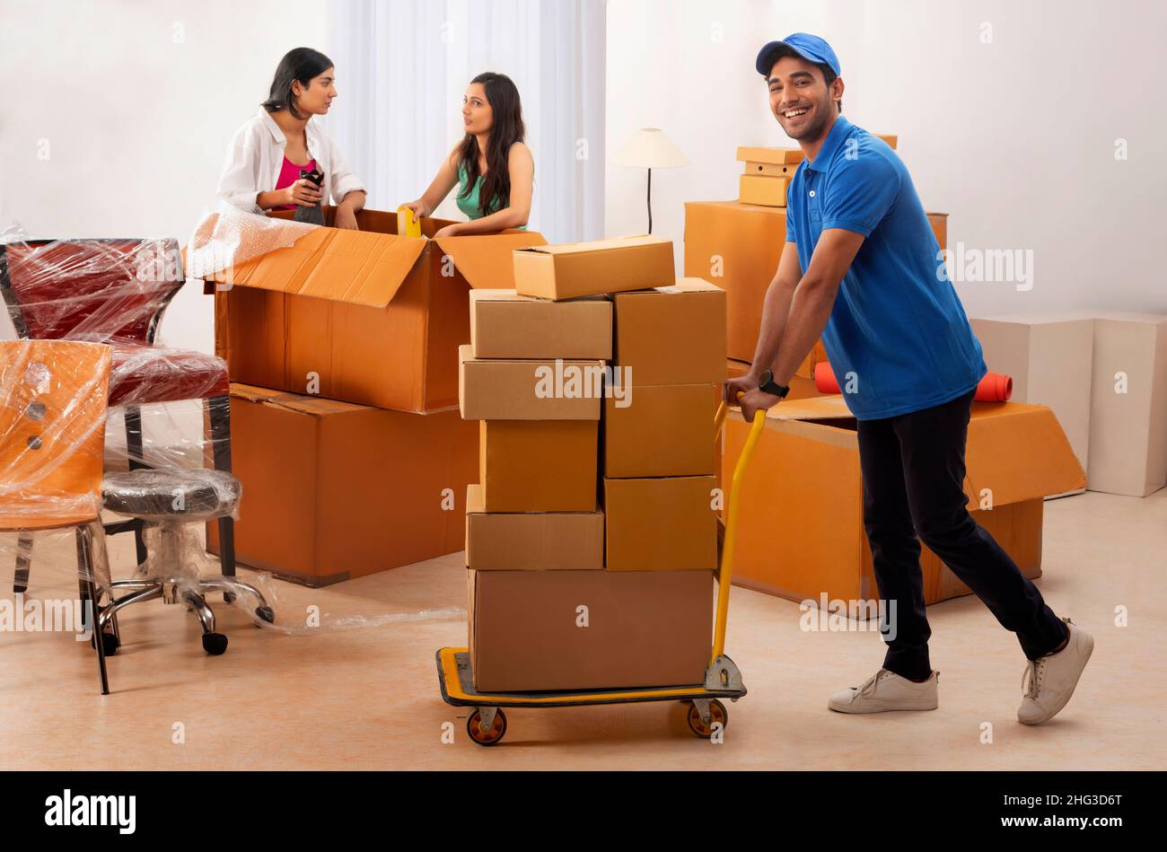 Girls busy with packing while the delivery boy moving boxes to new ...