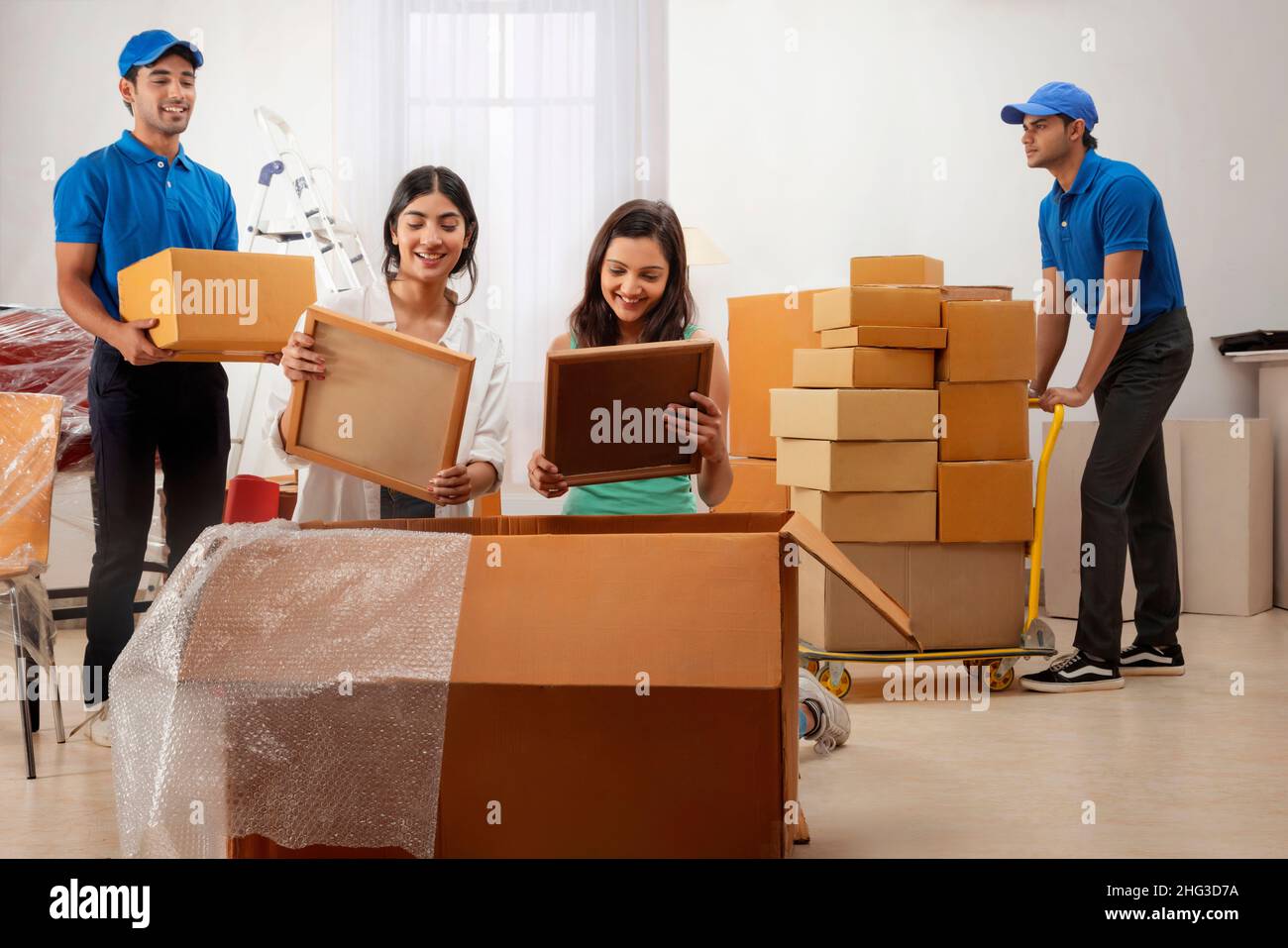 Delivery boys moving carton boxes and helping girls in packing Stock ...