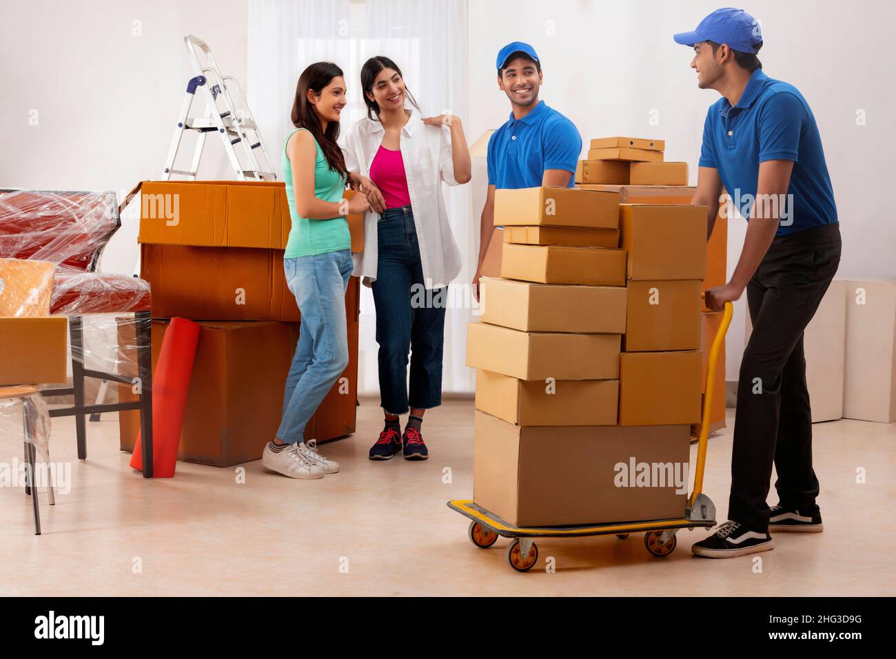 Adult girls and delivery boys standing together while the carton boxes ...