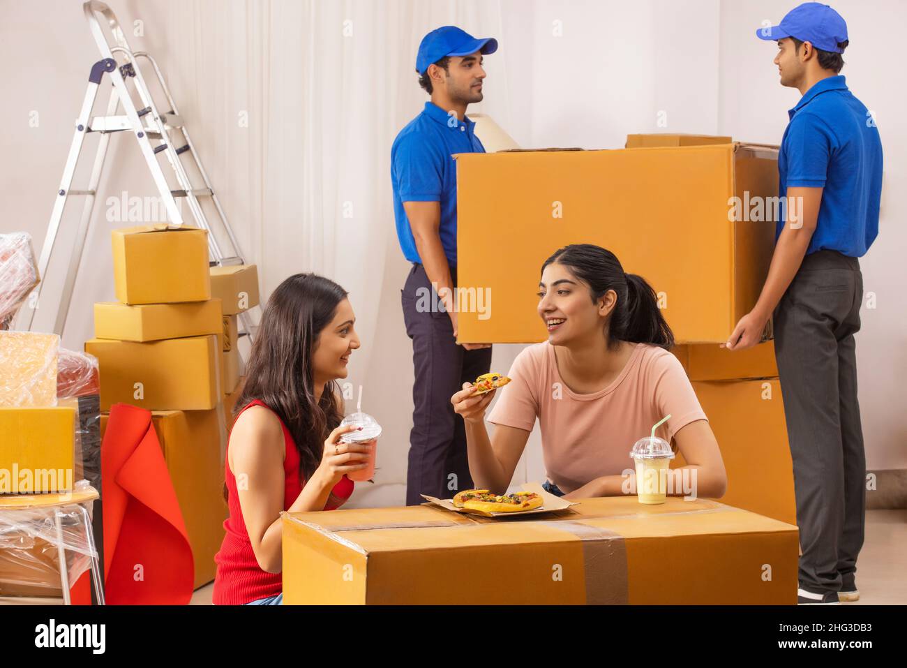 Adult girls eating pizza and drinking shake while the delivery boys ...