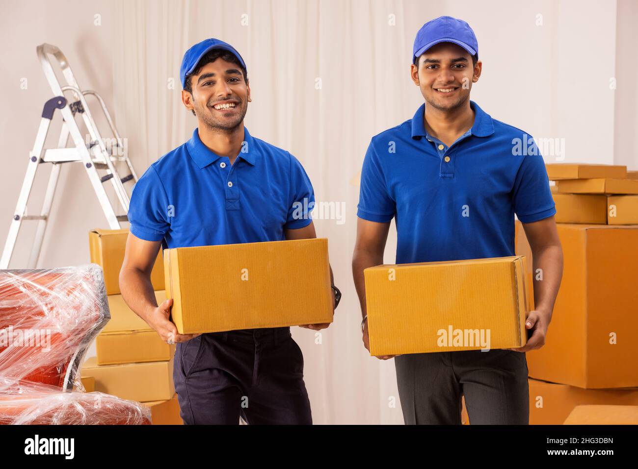 Delivery boys in uniform standing with cardboard boxes Stock Photo - Alamy