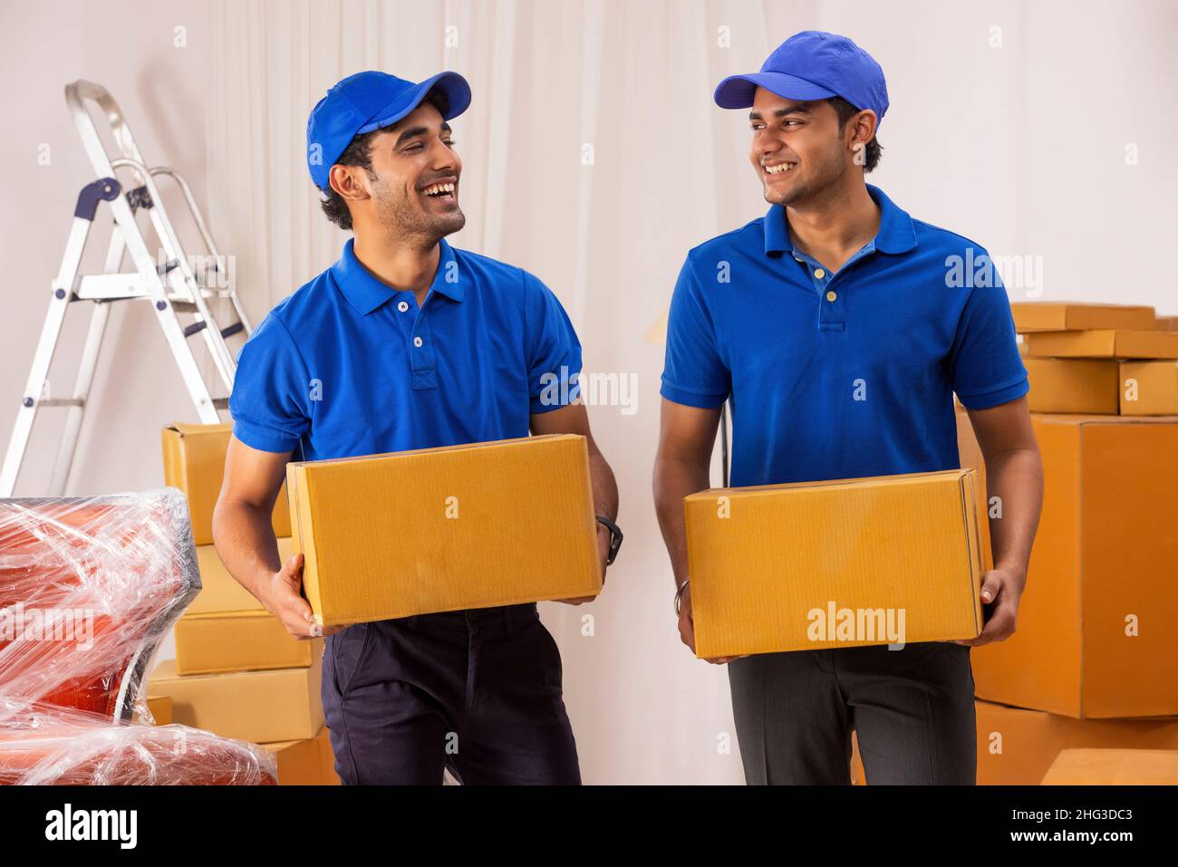 Delivery boys in uniform standing with cardboard boxes Stock Photo - Alamy