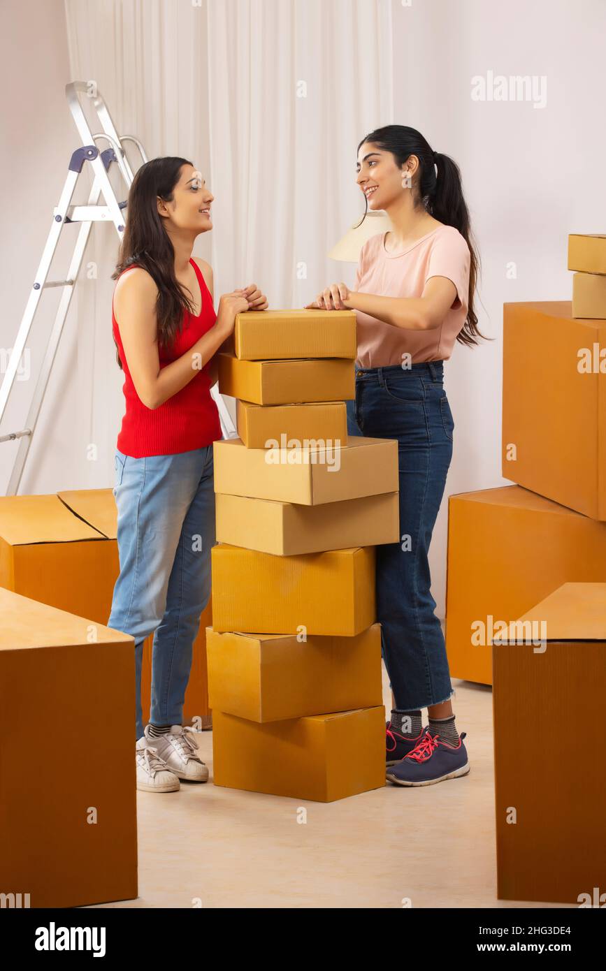 Adult girls standing together beside the stack of cardboard boxes Stock ...