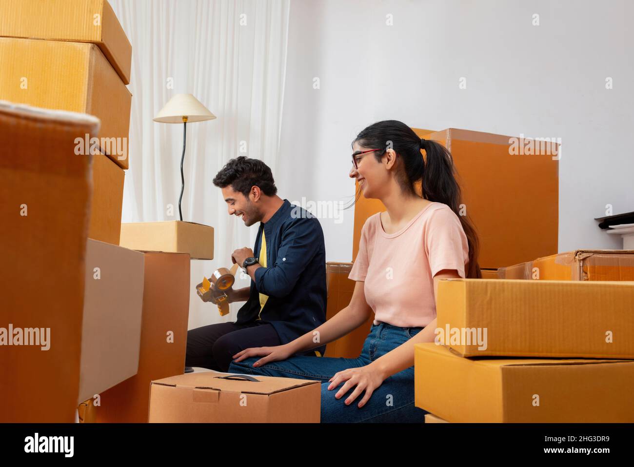Adult boy and girl smiling together during packing of carton boxes ...