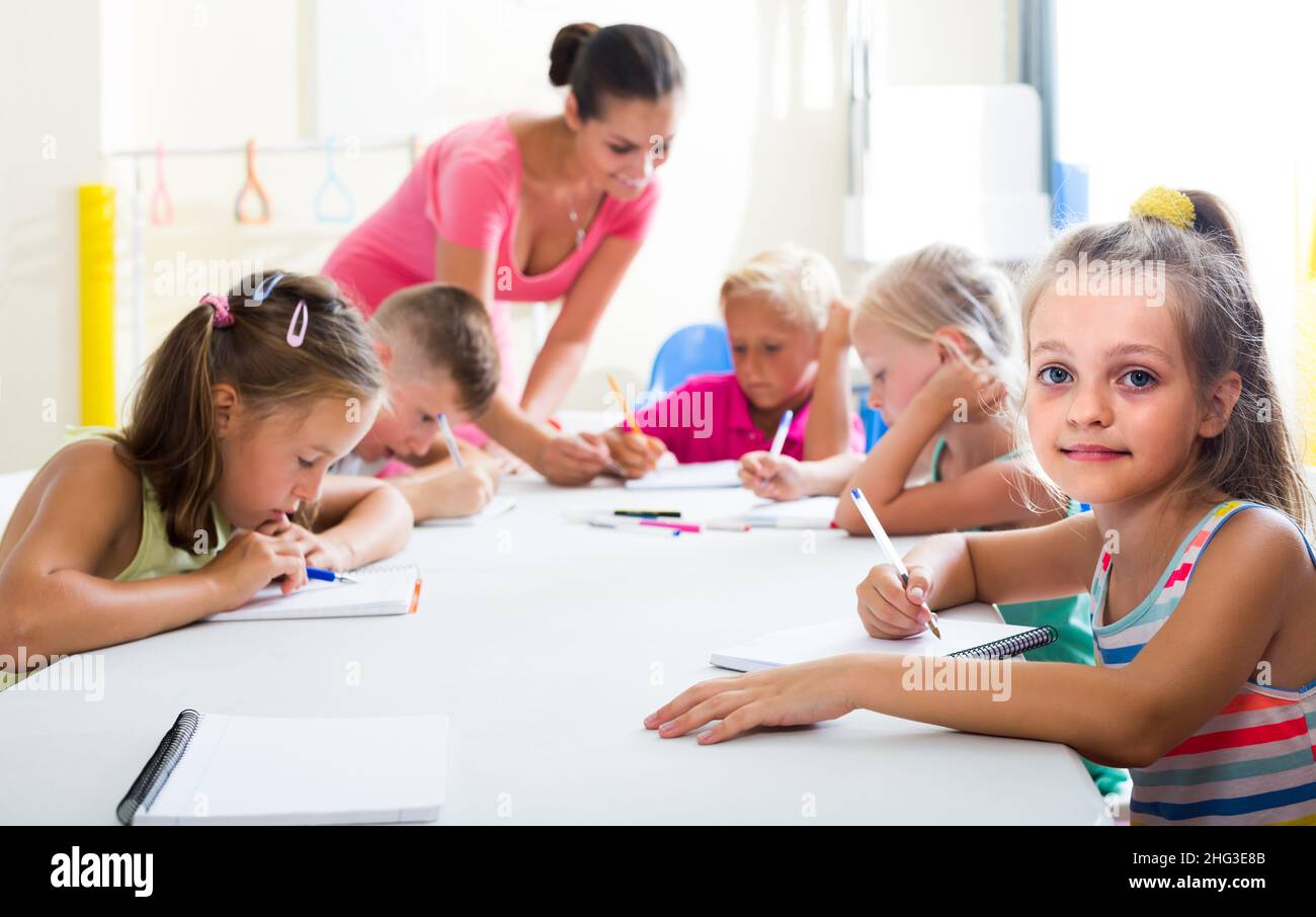 children making writing exercises with help of teacher in class Stock ...