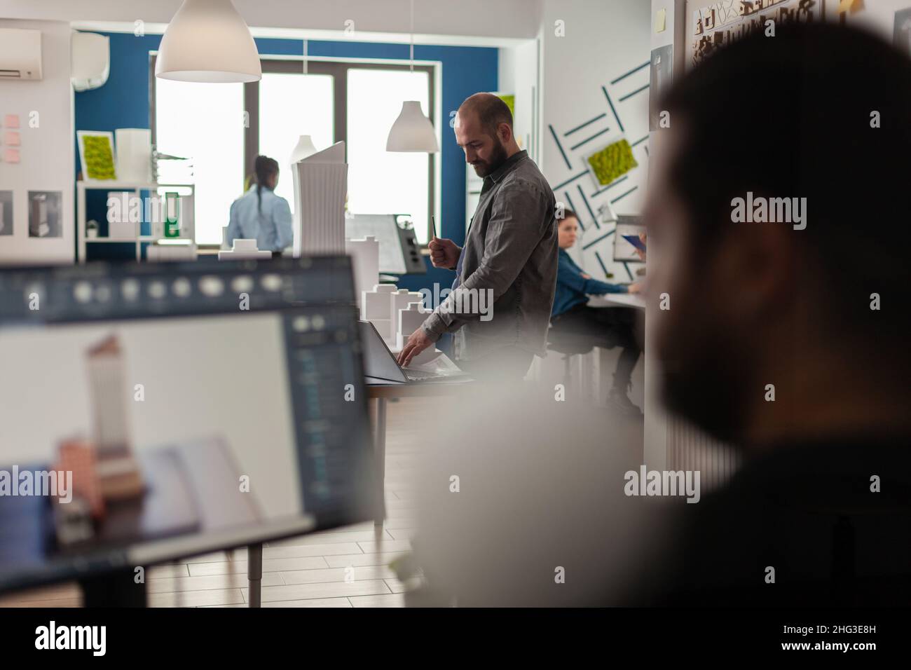 Engineer looking at blueprints on laptop at desk with architectural ...