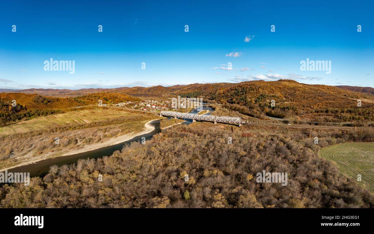 Long railroad bridge over narrow shallow river leading to mountain ...