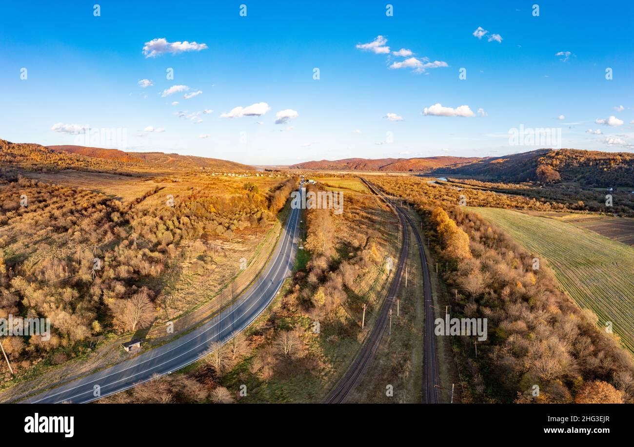 Long railroad bridge over narrow shallow river leading to mountain ...