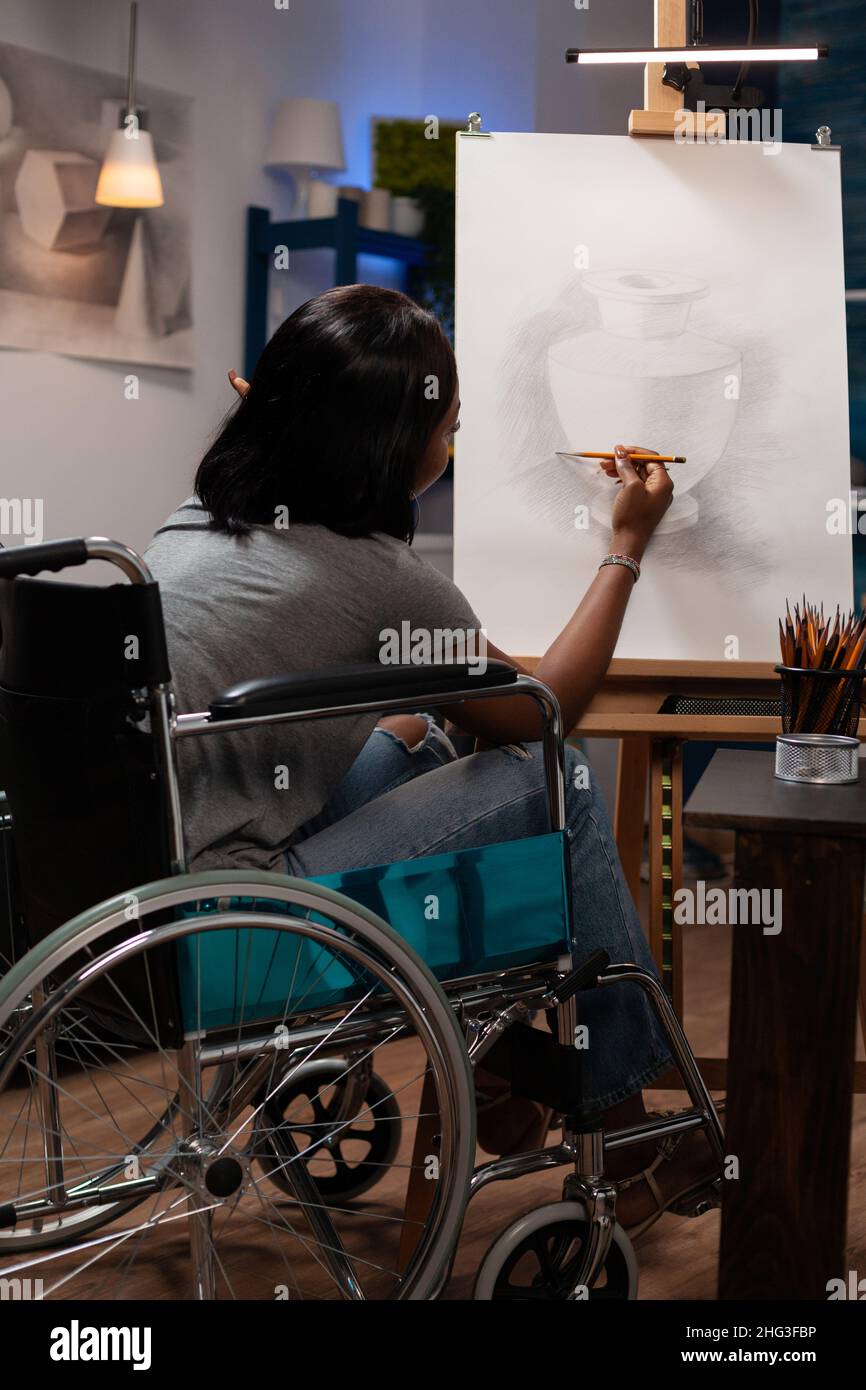 Young woman artist with disability drawing vase on canvas using ...