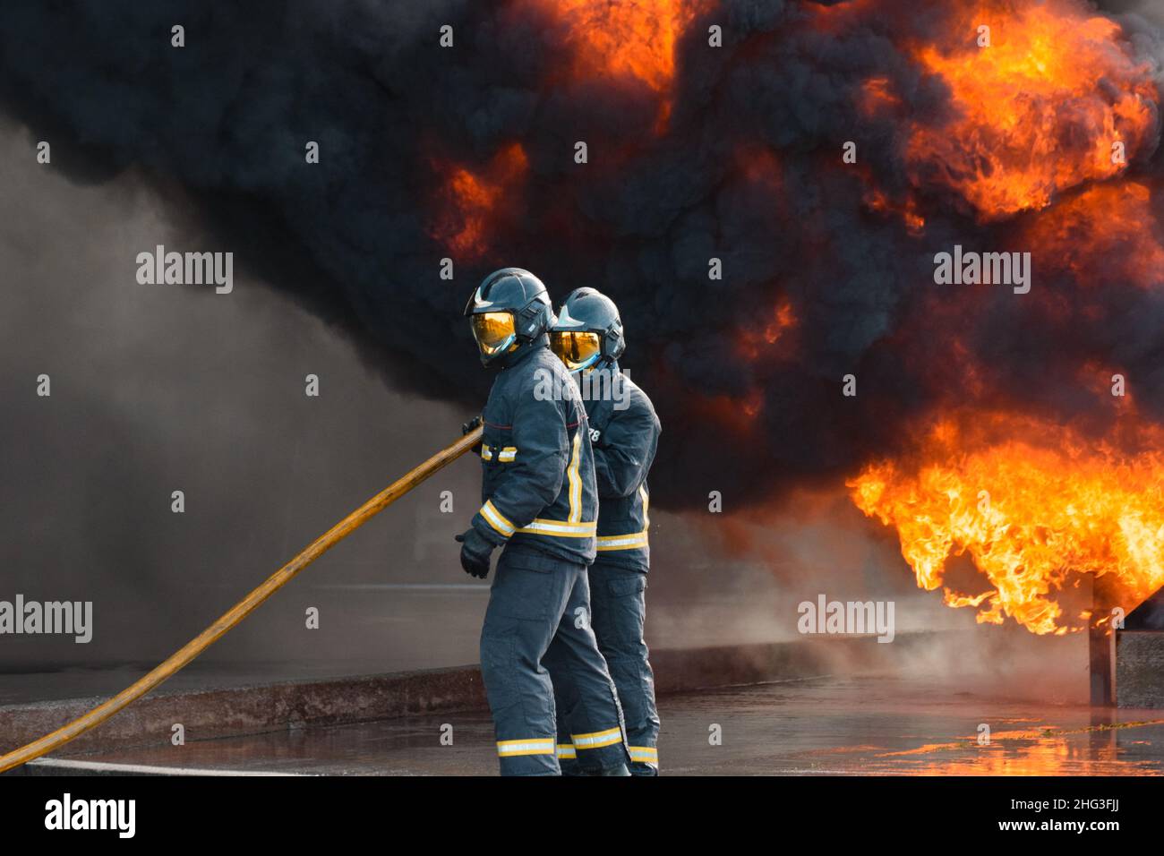 Group of firefighters putting out a fire surrounded by smoke Stock ...