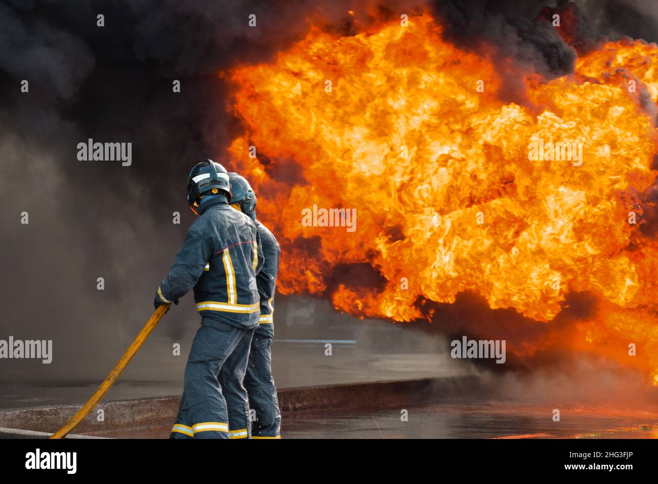 Group of firefighters putting out a fire surrounded by smoke Stock ...