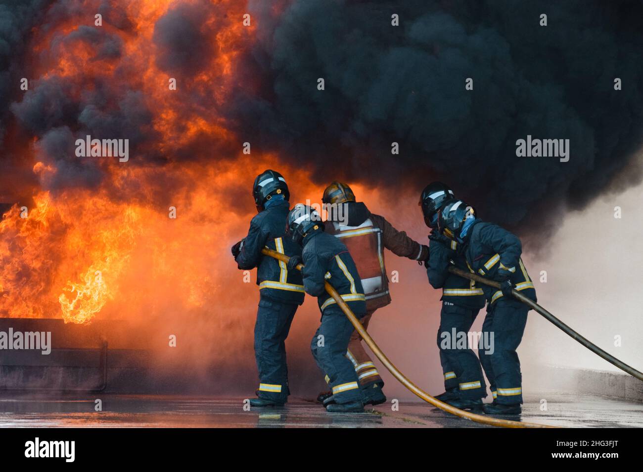 Group of firefighters putting out a fire surrounded by smoke Stock ...