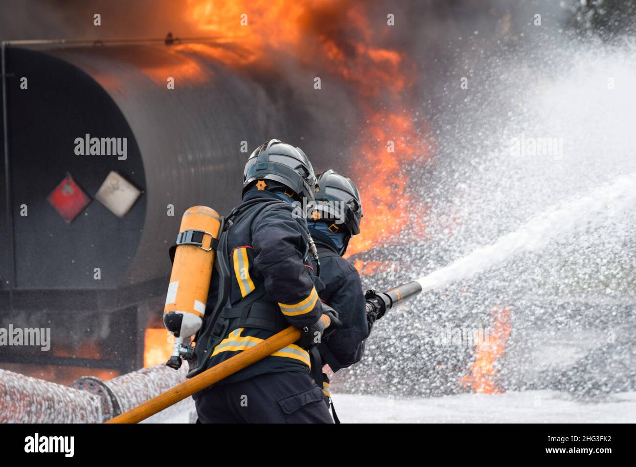 Group of firefighters putting out a fire surrounded by smoke Stock ...