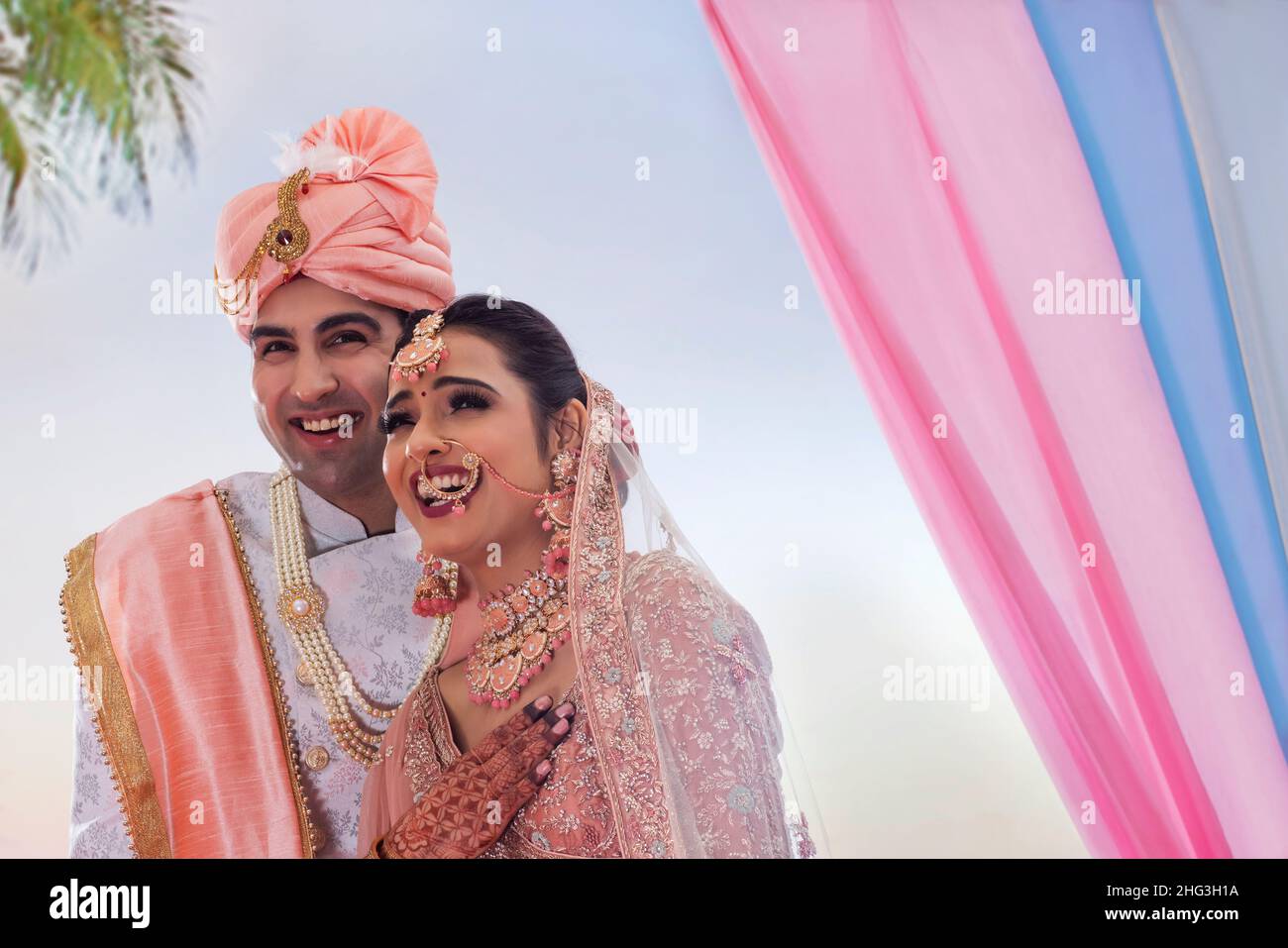 Indian bride and groom in traditional wedding dress smiling together ...