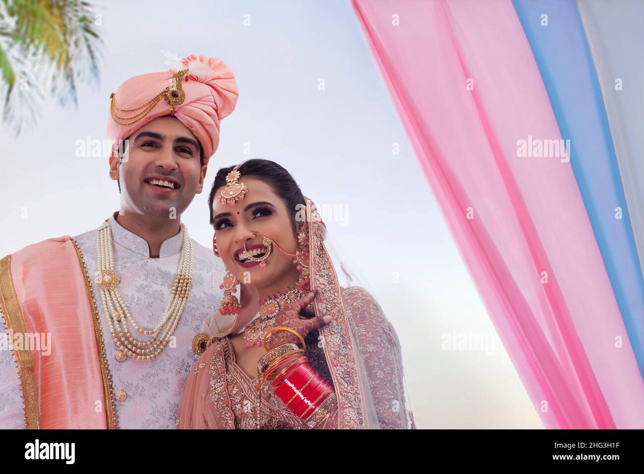 Indian bride and groom in traditional wedding dress smiling together ...