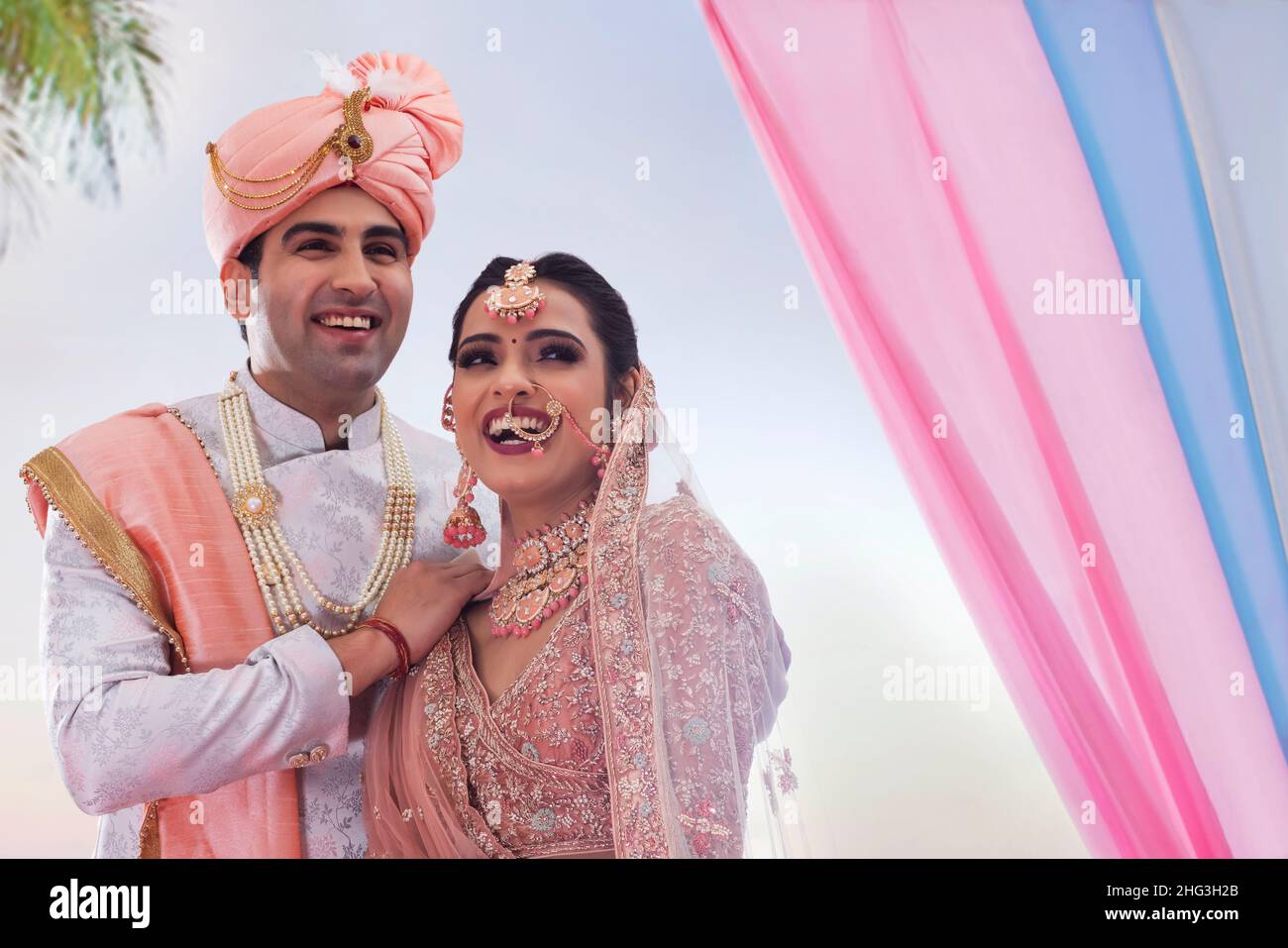 Indian bride and groom in traditional wedding dress smiling together ...
