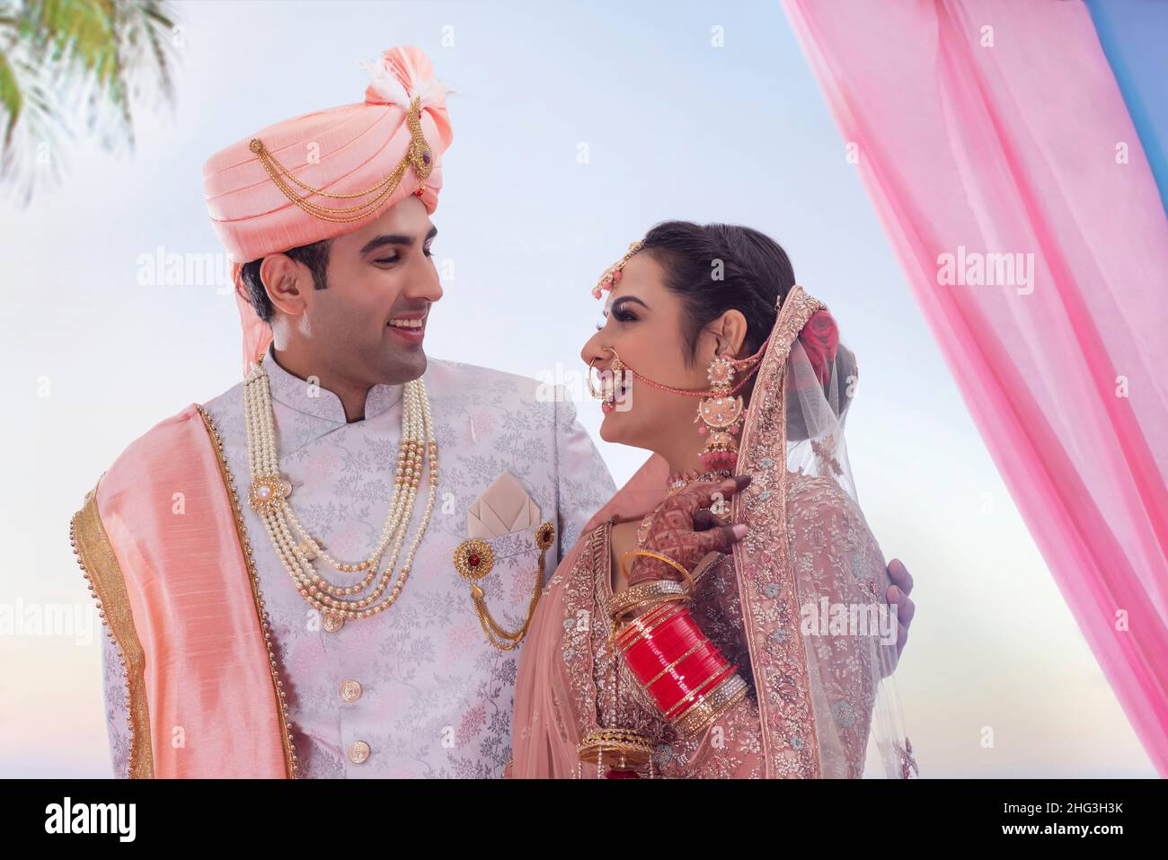 Indian bride and groom in traditional wedding dress smiling and looking ...