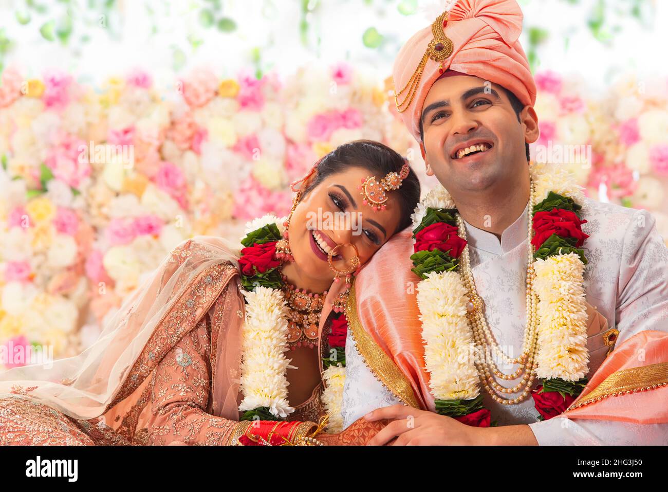 Portrait of a happy Indian wedding couple sitting together on mandap ...