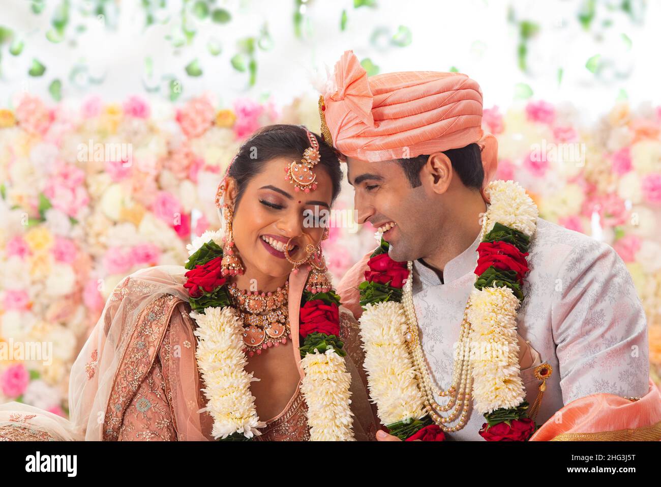 Portrait of a happy Indian wedding couple sitting together on mandap ...
