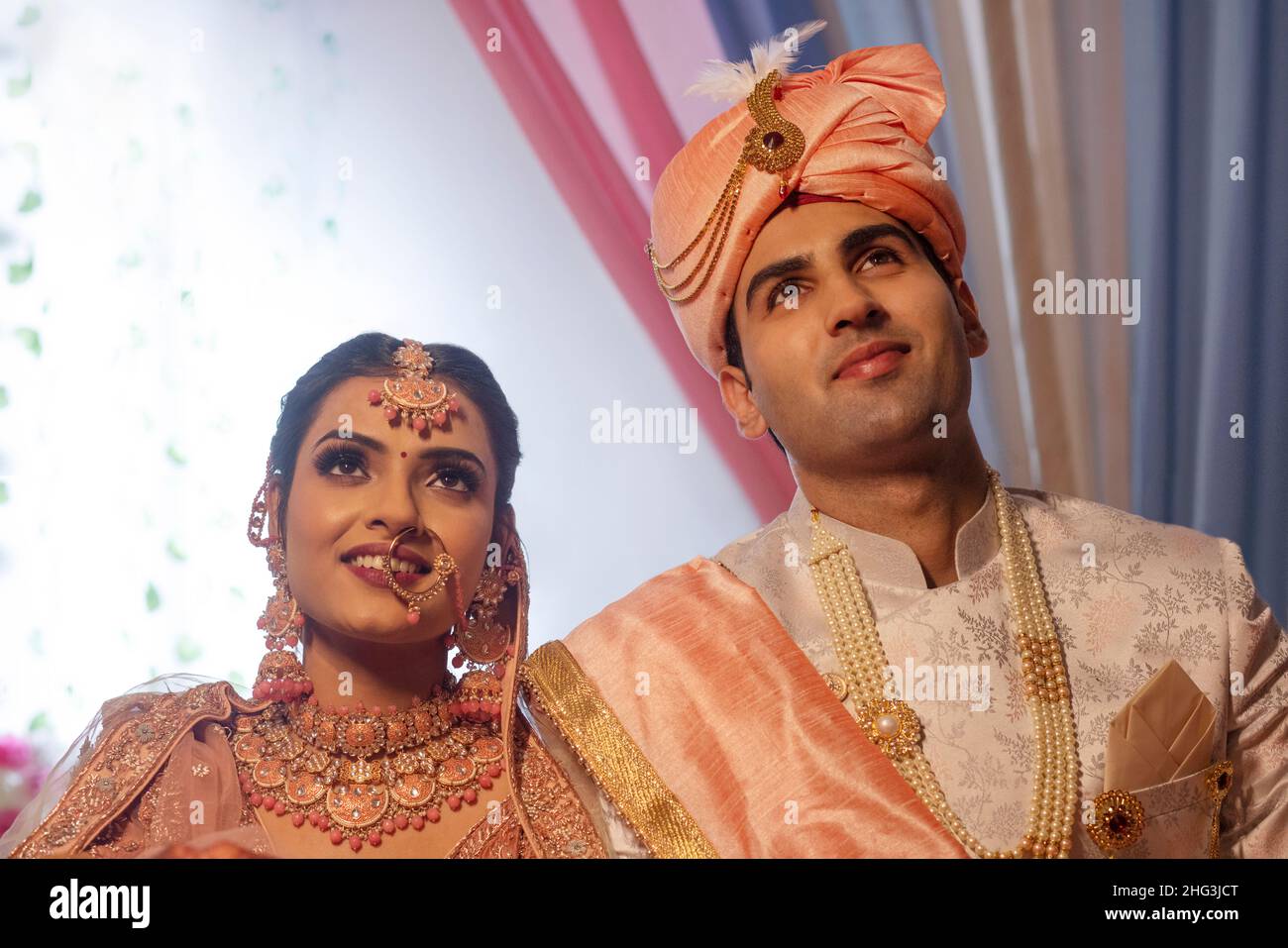 Portrait of a happy Indian wedding couple standing together during ...