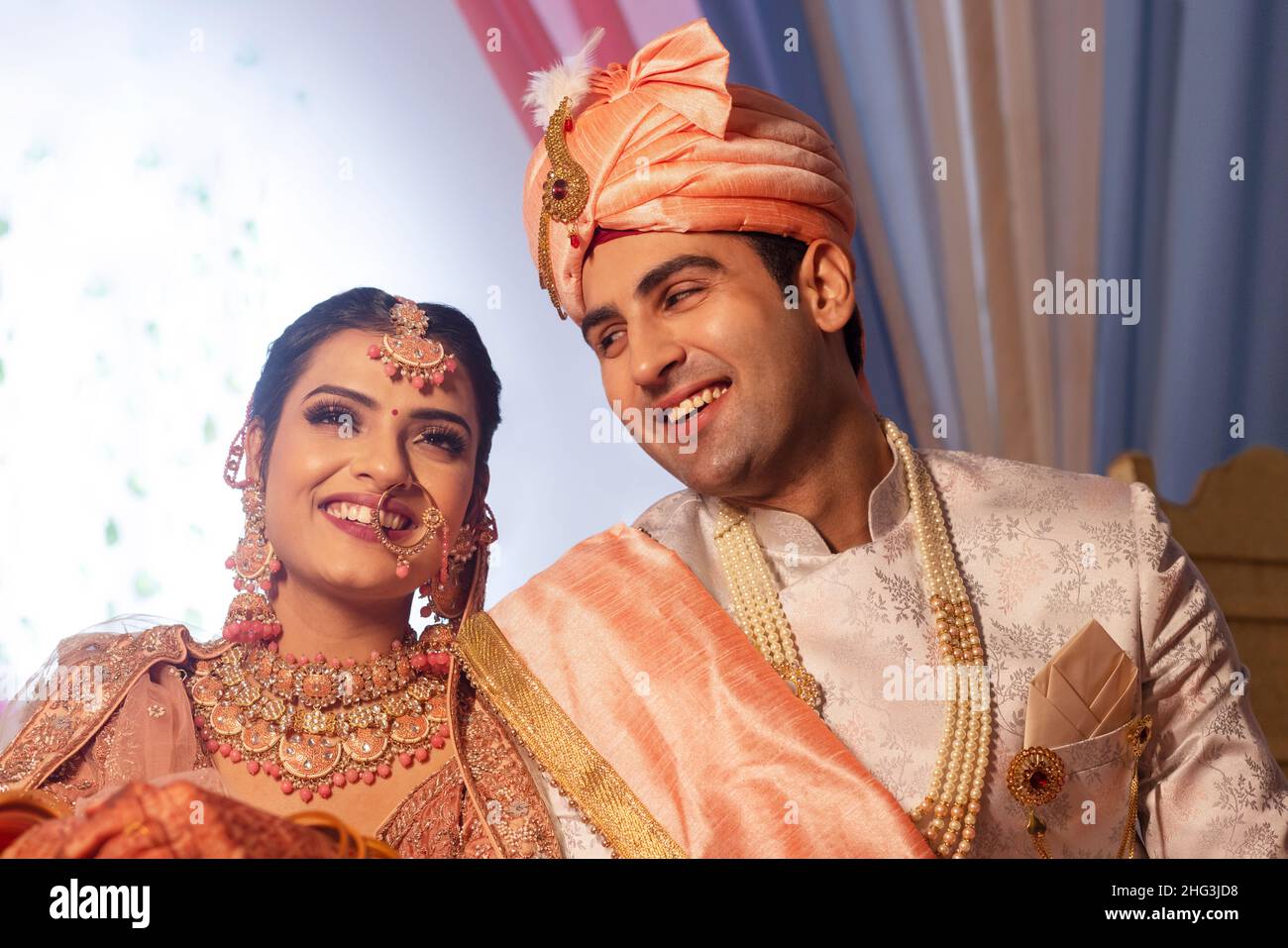 Portrait of a happy Indian wedding couple standing together during ...