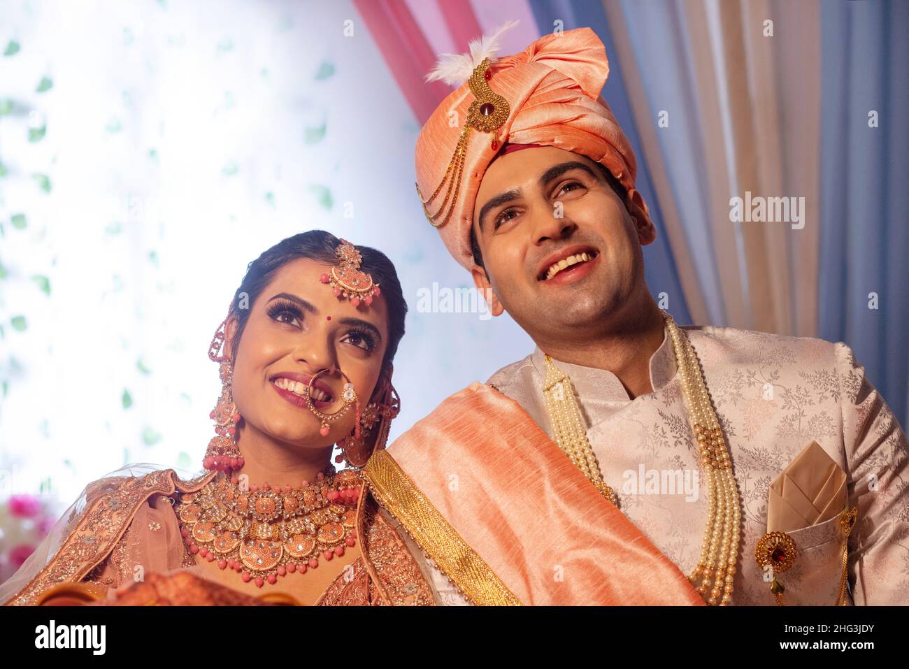 Portrait of a happy Indian wedding couple standing together during ...