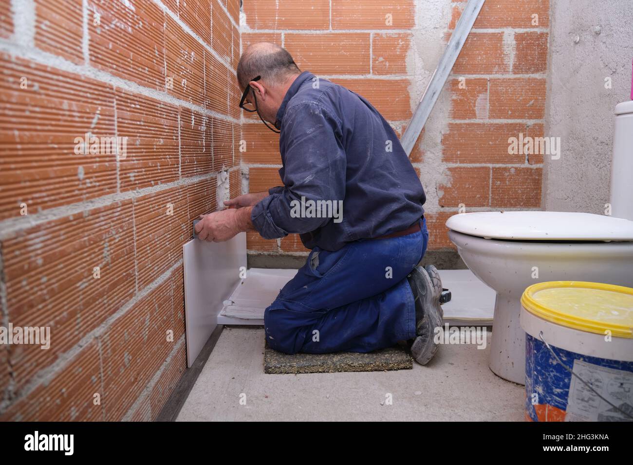 Senior constructor worker laying white ceramic tiles on the wall Stock ...