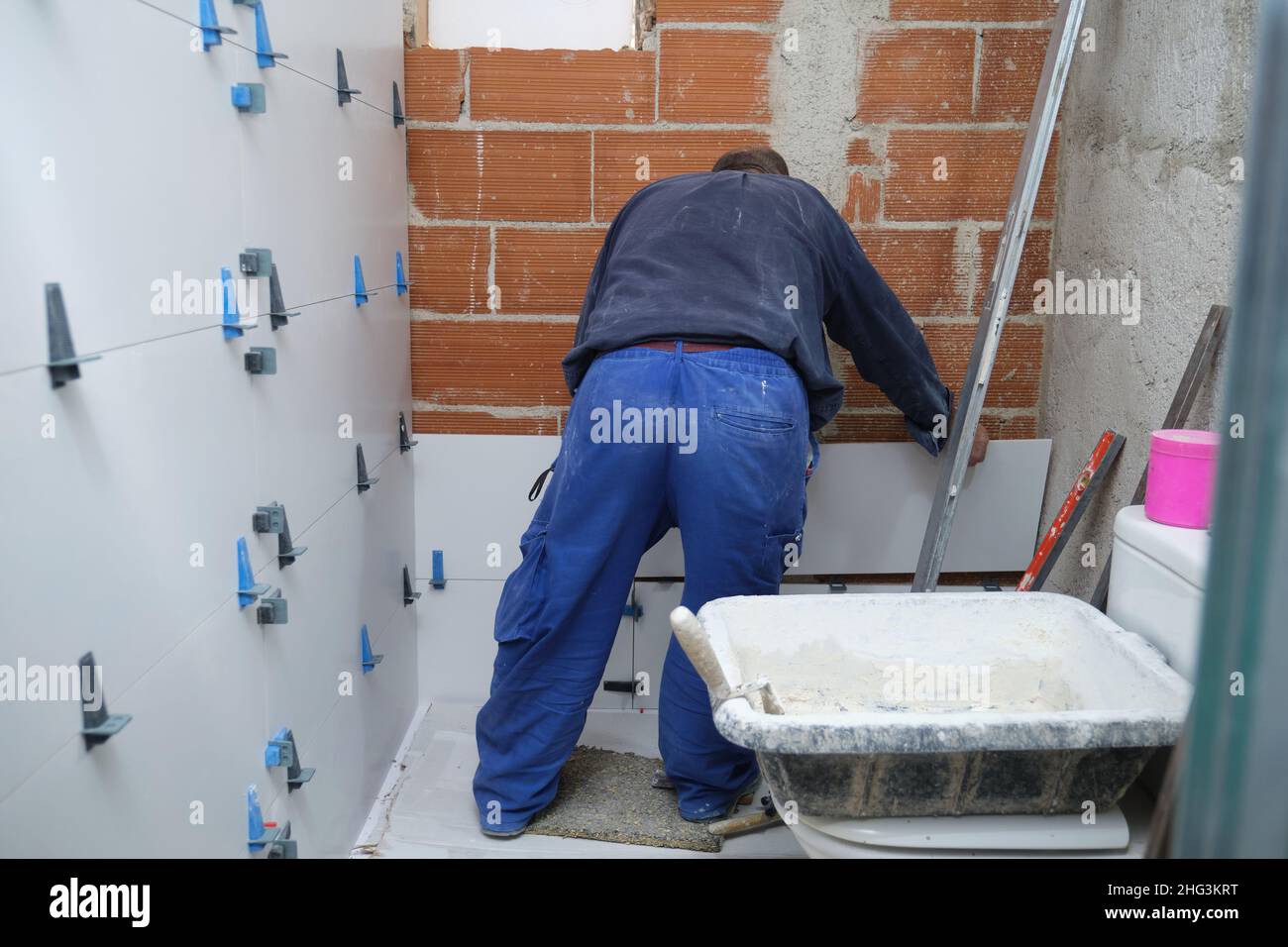 Professional tiler placing white ceramic tiles on the wall Stock Photo ...