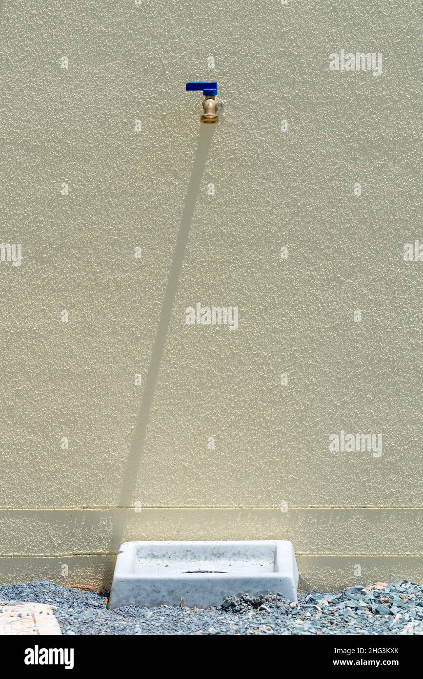 A modern outside tap or faucet mounted on a painted concrete wall with ...