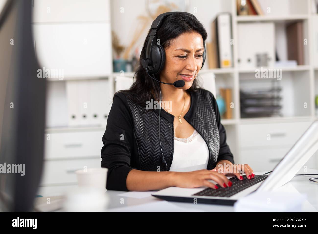 Friendly female call center operator receiving calls in office Stock ...