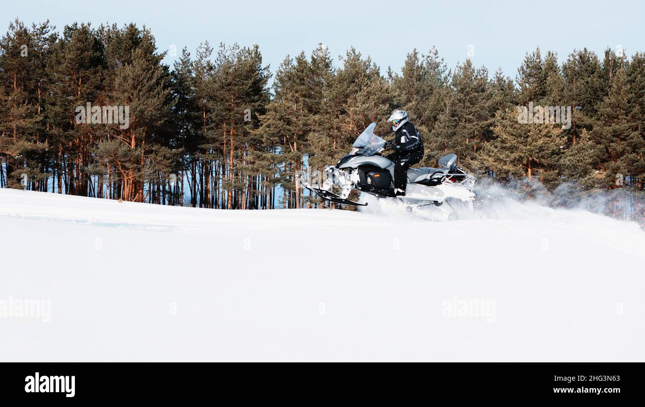 Snowmobile rider driving fast. Riding with fun in white snow powder ...