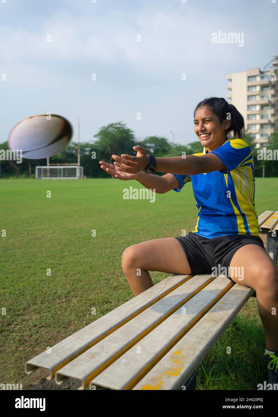 Young rugby player trying to catch the rugby ball while sitting on ...