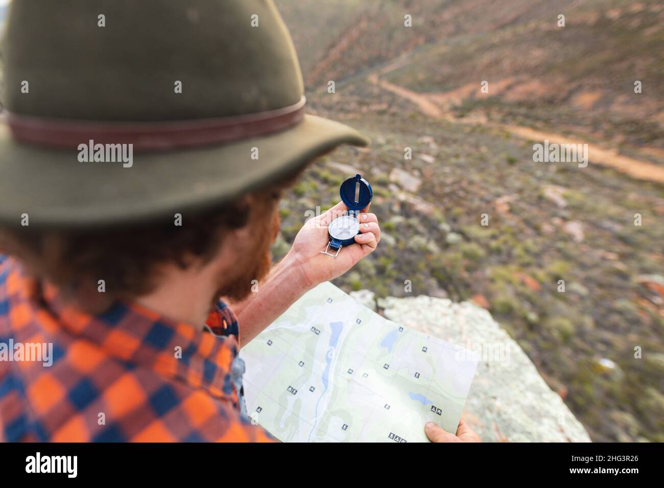 Young male caucasian hiker checking navigational compass at mountain ...
