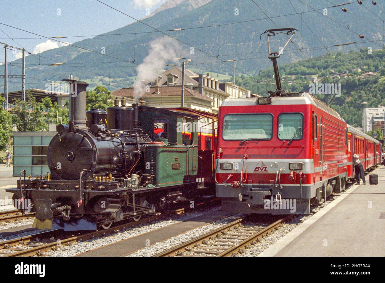 A steam locomotive and an electric passenger train at Brig, Switzerland ...