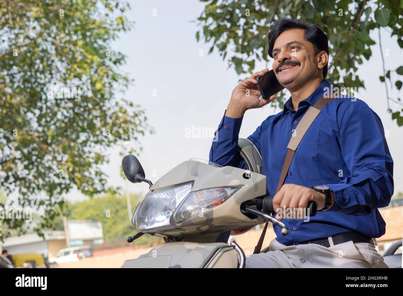 Man talking on Smartphone while sitting on scooty Stock Photo - Alamy