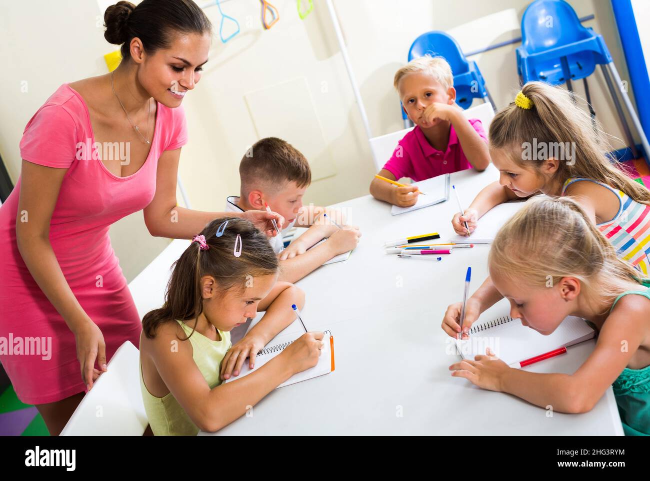 children making writing exercises with help of teacher in class Stock ...