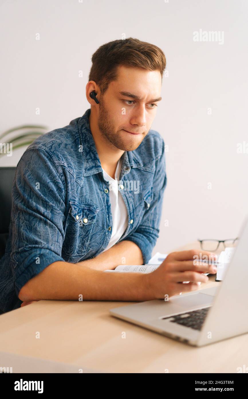 Vertical shot of serious young business man in earphone having online ...