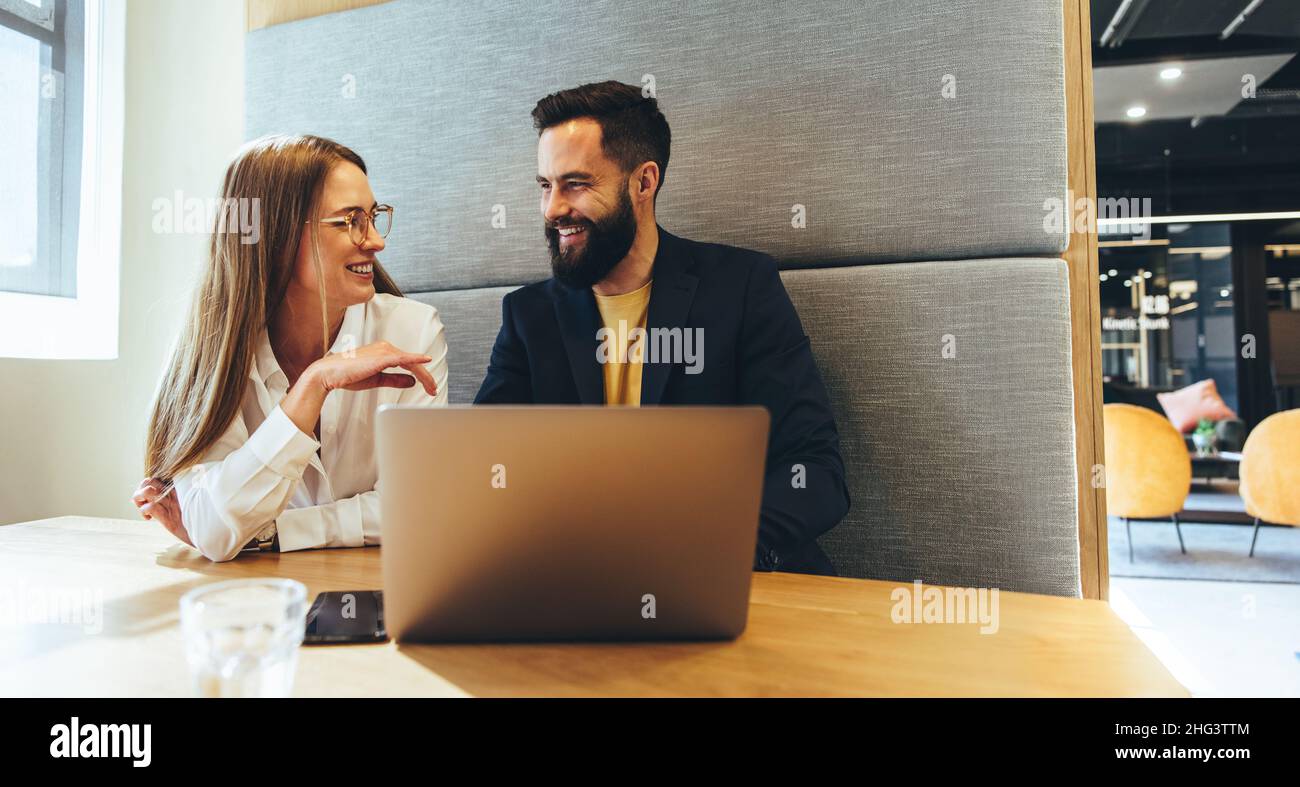 Young professionals smiling at each other in a modern workspace. Two ...