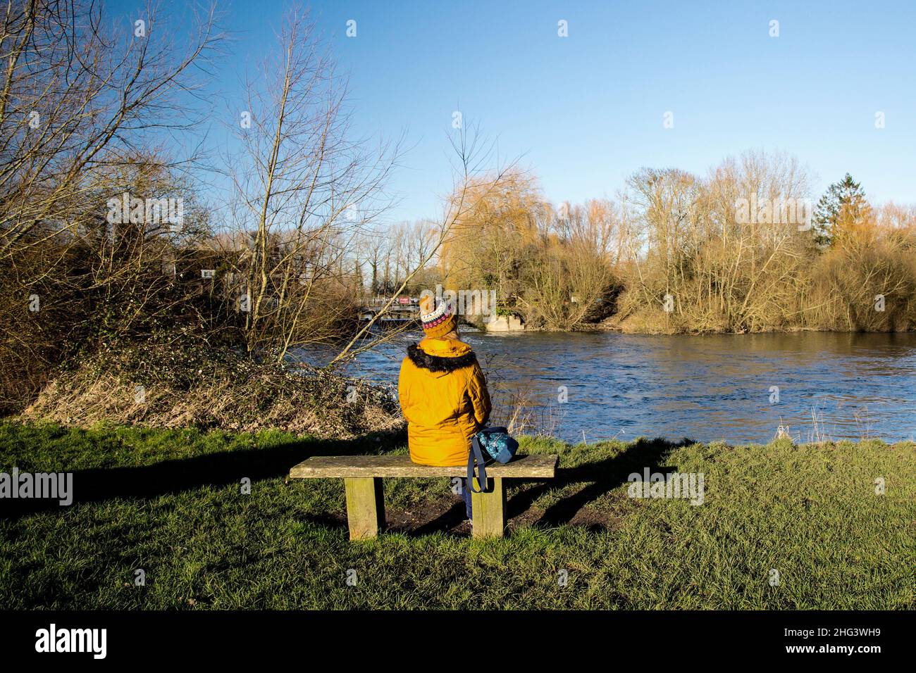 A woman wearing a bright yellow jacket and hat sits gazing at Buscot ...